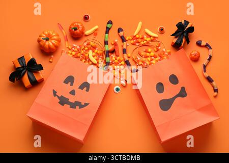 Composition with paper bags and tasty candies for Halloween on orange ...