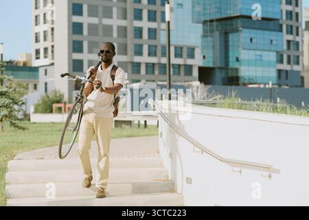 Young black man walking down the street carrying a briefcase and a ...