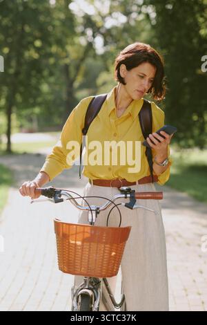 Woman using phone while standing by bicycle on city street Stock Photo ...
