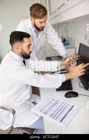 Two doctors discussing medical card of patient in office Stock Photo ...