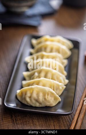 Plate with tasty Japanese gyoza and sauce on color background Stock ...