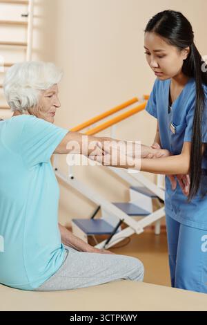 Physical therapist Asian woman, doing leg physiotherapy for elderly man ...