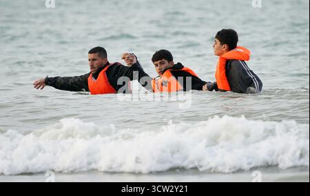 People thought to be migrants wade through the sea to board a small ...