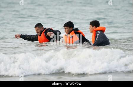 People thought to be migrants wade through the sea to board a small ...