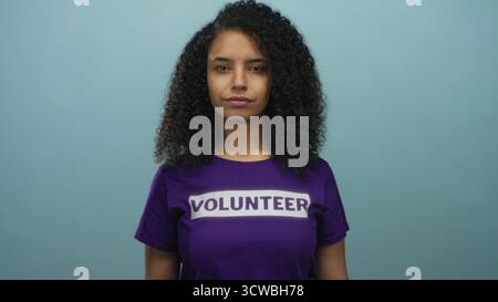 Young latin woman wearing volunteer uniform using laptop at charity ...