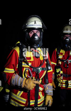A firefighter in a dark uniform and helmet is the central figure, with ...