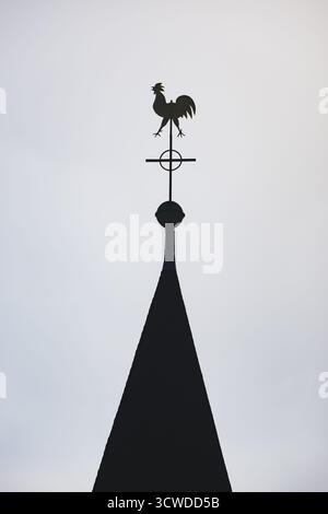 Vertical White steeple on top of the pitched roof of a church with ...