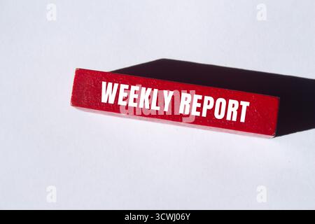 Weekly report message written on ripped torn blue paper piece with red ...