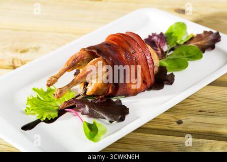 Baked in bacon small quail with balsamic sauce, served with lettuce ...