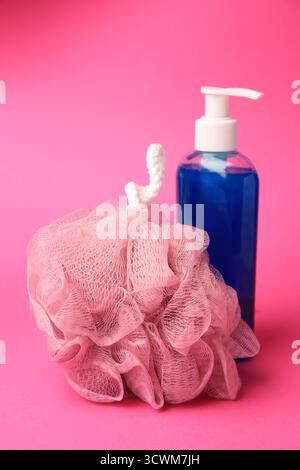 Pink shower puff, bottle of cosmetic product and towel on light blue ...