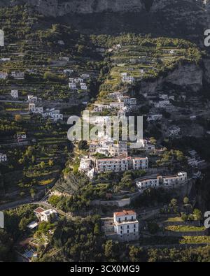 Aerial view of a green cliffside with a town nestled on top amidst a ...