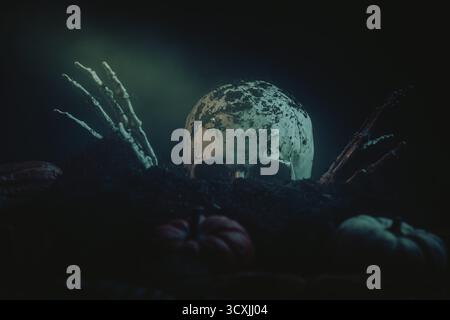 Halloween scene with a skull, skeletonised hands and pumpkins in dark ...