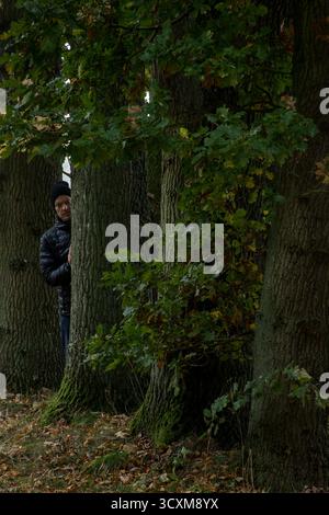 Scary stalker hiding behind tree looking out in scary creepy situation ...