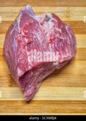 Large piece of raw pork meat on wooden cutting board. Fresh ingredients ...