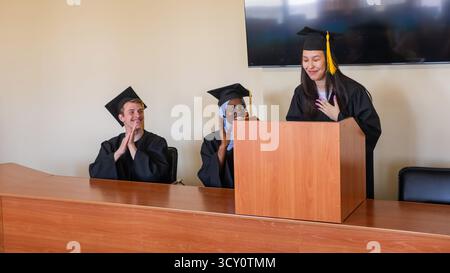 A young woman stands at the lectern and delivers a graduation speech to ...