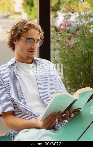 Thoughtful young man reading book on yellow background Stock Photo - Alamy