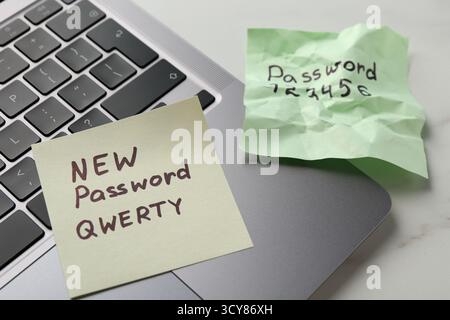 Changing password. Notes with new and old passwords and laptop on green ...