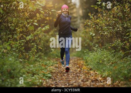 Blond girl running among trees Stock Photo - Alamy
