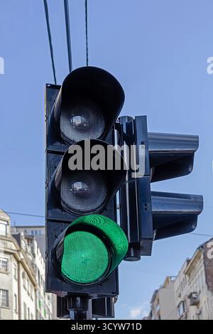 An urban city street with a green light for two traffic lights against ...