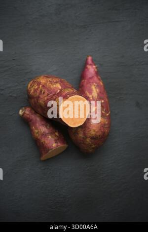 From above of raw sweet potatoes and fresh red oca in carton box placed ...