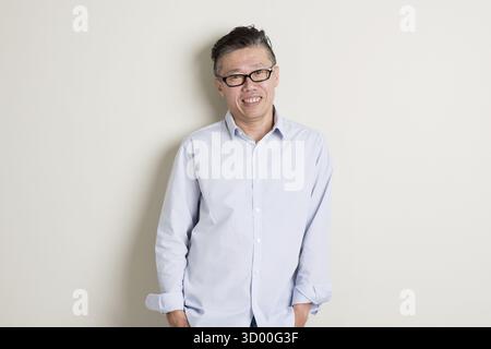 Portrait of single mature 50s Asian man in casual business standing ...