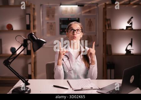 Surprised doctor, physician pointing fingers left and looking at logo ...