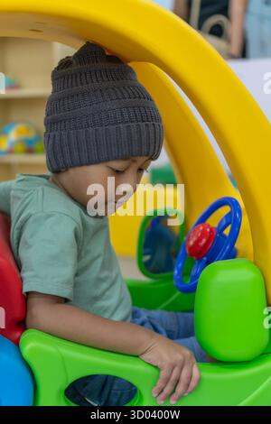 Child boy is learning to knit. Colorful wool yarns are on the wooden ...