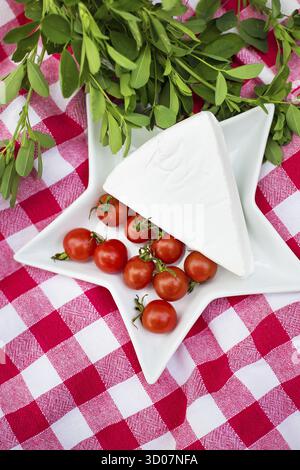 brie cheese and cherry tomatoes on a red tablecloth Stock Photo - Alamy