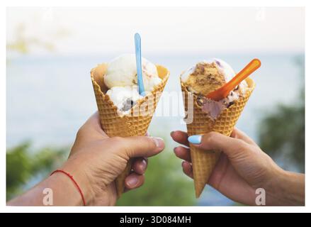 Female hands with different sweet ice-cream in waffle cones on red ...