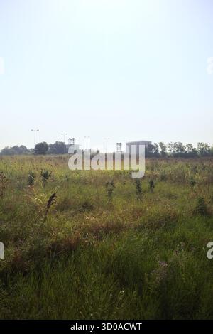 Field with an industrial complex in the distance on a summer day Stock ...