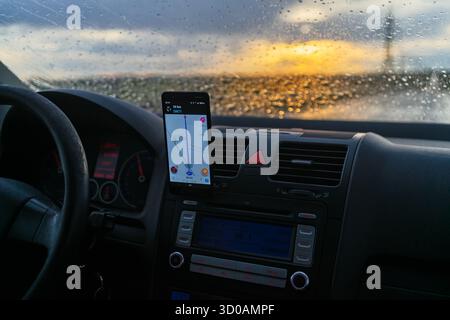 Driver using waze app on mobile phone mounted on car dashboard Stock ...