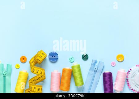 Thread spools, measuring tape and zippers on color background Stock ...