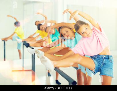Group of children doing leg stretch at ballet barre Stock Photo - Alamy