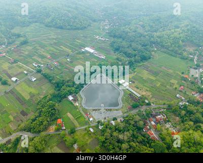 Aerial view of the serene Embung Imogiri reservoir reflecting the sky ...