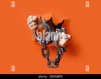 Hands in Metal Shackles. Two clenched hands in chained metal shackles ...