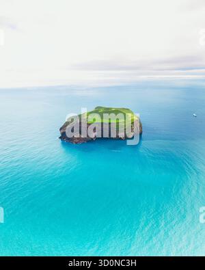 Aerial view of a solitary, verdant island rising from the turquoise sea ...