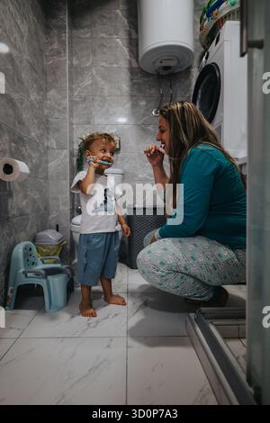 Mother brushing teeth to happy toddler baby boy. Mom woman brushes ...