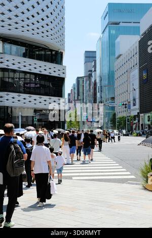 Pedestrians, tourists, and shoppers walking on sidewalk along Ginza ...