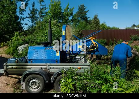 An operator loads tree branches into a wood chipper Stock Photo - Alamy
