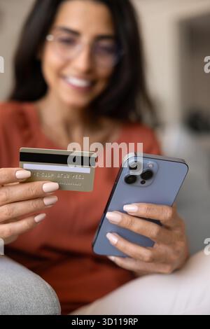 Woman with credit card using mobile phone in bedroom Stock Photo - Alamy