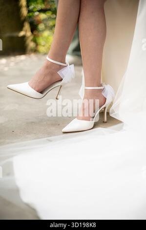 Wedding shoes for the bride. White high-heeled shoes near wedding rings ...