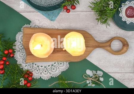Wooden plates with burning candles on end table near grey wall Stock ...