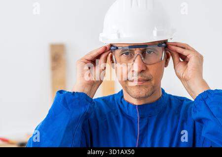 Construction worker putting protective eyeglasses in a house under ...