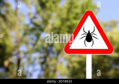 Warning sign marking habitat of ticks in forest Stock Photo - Alamy