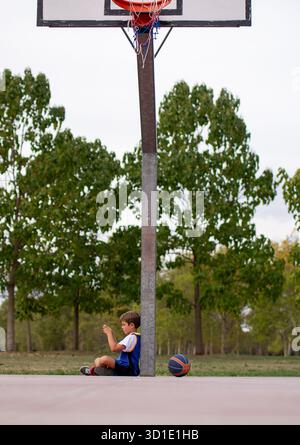 Lonely Boy with Gadget on an Empty Basketball Court, vertical photo ...