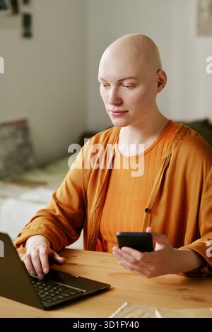 Young adult woman using smartphone and laptop for remote work outdoors ...