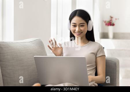 Asian woman waving during video call on laptop computer smiling happy ...