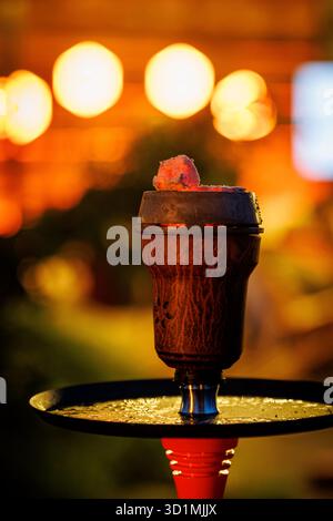 hookah bowl, shisha and coals close-up on black background with colored ...