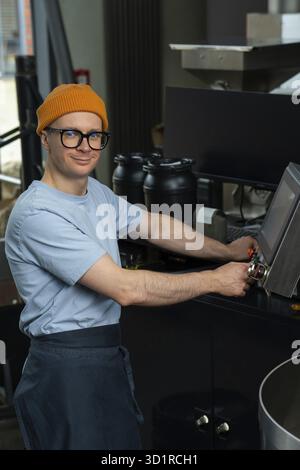 Modern coffee roasting factory, man operating process of creating ...