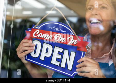 Happy Female Store Owner Turning Open Sign in Window Stock Photo - Alamy